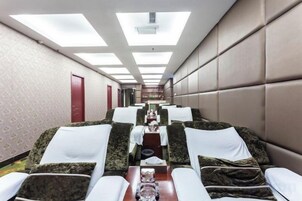 Quarto de hotel com um corredor extenso, várias camas e uma mesa central com amenidades.