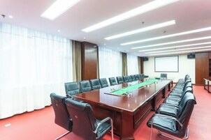 Uma sala de conferências com uma mesa comprida, várias cadeiras e uma tela de projeção.