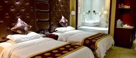 Quarto de hotel com duas camas, um espelho grande e vista para um banheiro.