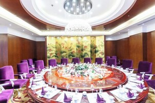 Uma sala de conferência com uma mesa redonda, cadeiras roxas e um lustre.