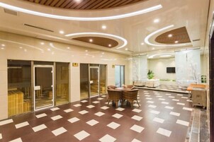 Um saguão de hotel com balcão de check-in, área de estar e um espelho grande.