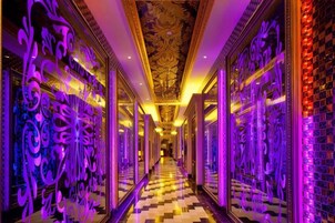 Um corredor com decorações elaboradas nas paredes e piso xadrez.