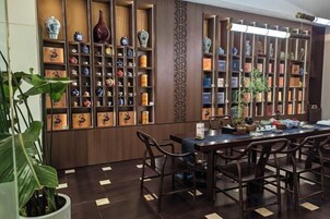 Uma sala de jantar com uma mesa comprida e cadeiras, rodeada por prateleiras com diversos objetos.