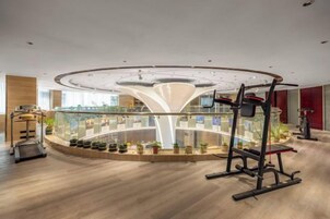 Uma academia com design circular central, equipamentos de ginástica e plantas em vasos.