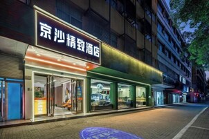 Um hotel com fachada moderna, grandes janelas de vidro e um letreiro de neon chamativo.