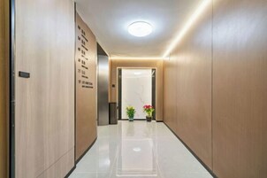 Um corredor moderno com paredes de madeira, piso polido e iluminação no teto.