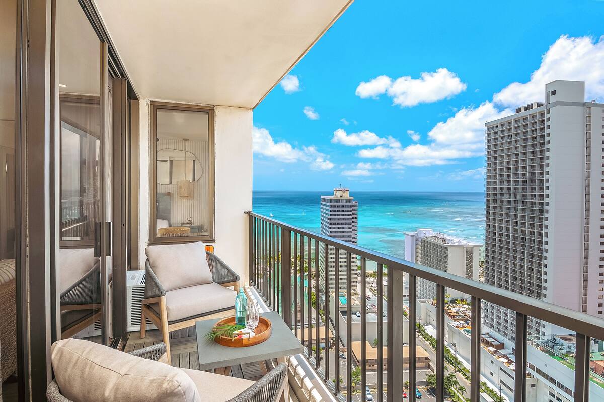 Uma varanda com vista para o oceano, uma mesa com bandeja e uma cadeira.