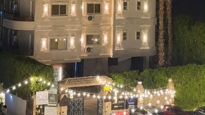 Um hotel de vários andares com varandas e uma estrutura iluminada em vermelho.