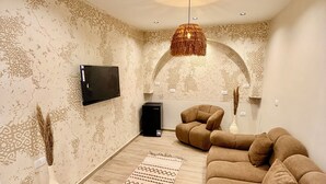 Uma sala de estar moderna com sofá, televisão, luminária pendente decorativa e paredes com padrão.