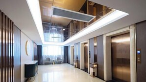 Um hall de hotel moderno com teto alto, um sistema central de ar condicionado e um mezanino.