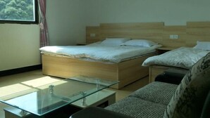 Quarto de hotel com cama de madeira, mesa de centro de vidro e um sofá.