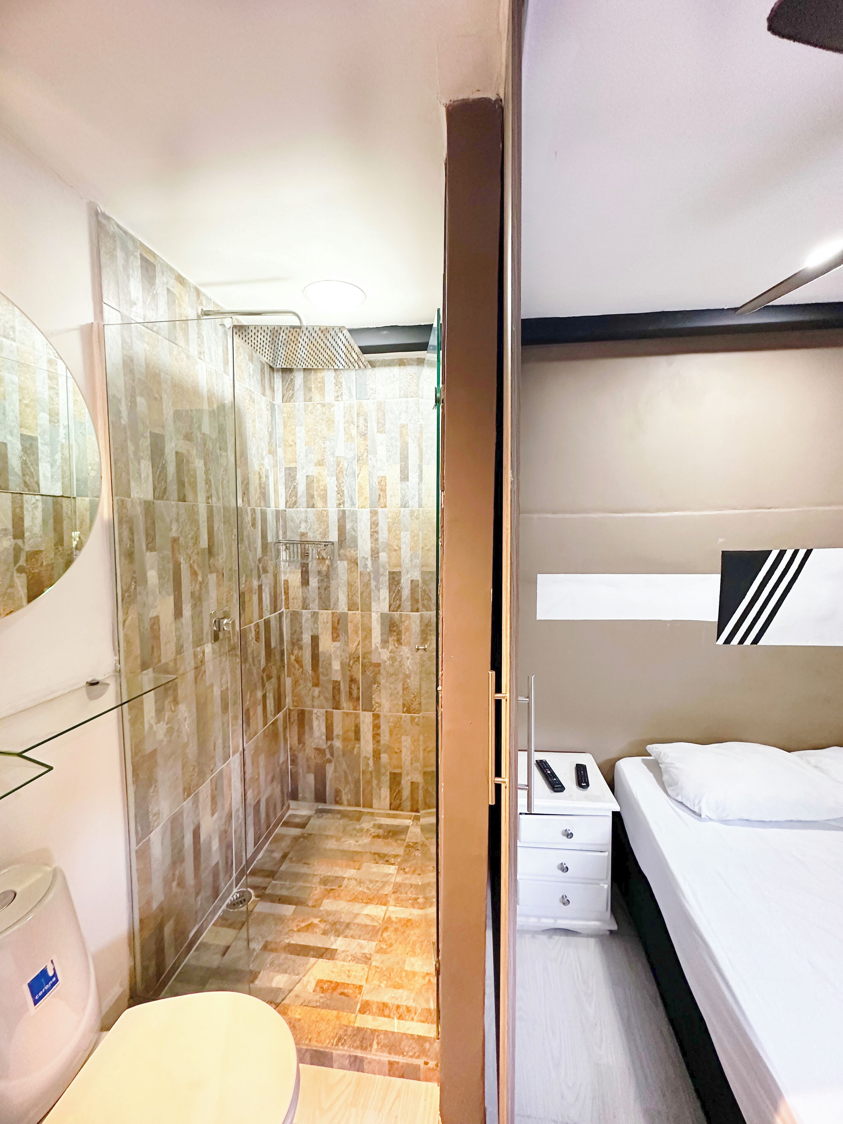 Quarto de hotel com chuveiro, vaso sanitário e cama.
