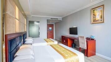 Quarto de hotel com uma cama grande, uma escrivaninha, uma cadeira, uma televisão e um quadro na parede.