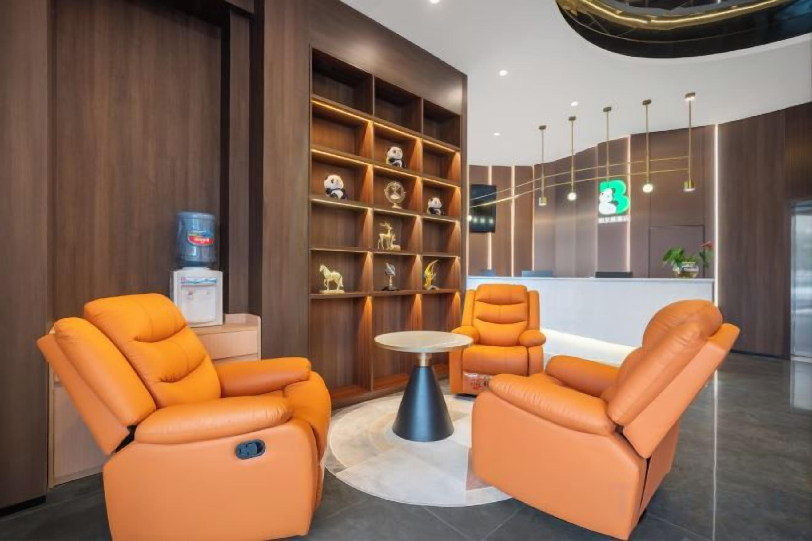Um hall com poltronas de couro, balcão de recepção e uma grande estante de livros.