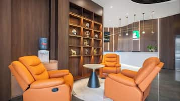 Um hall com poltronas de couro, balcão de recepção e uma grande estante de livros.