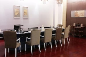 Uma sala de conferências com uma mesa comprida, cadeiras, um projetor e um quadro branco.