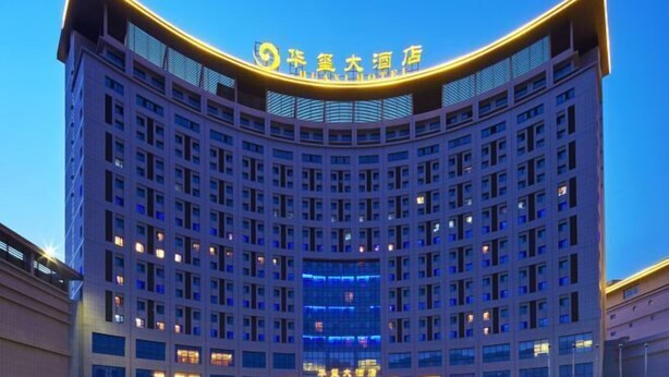 Edifício de hotel com várias andares, fachada curva e letreiros iluminados.