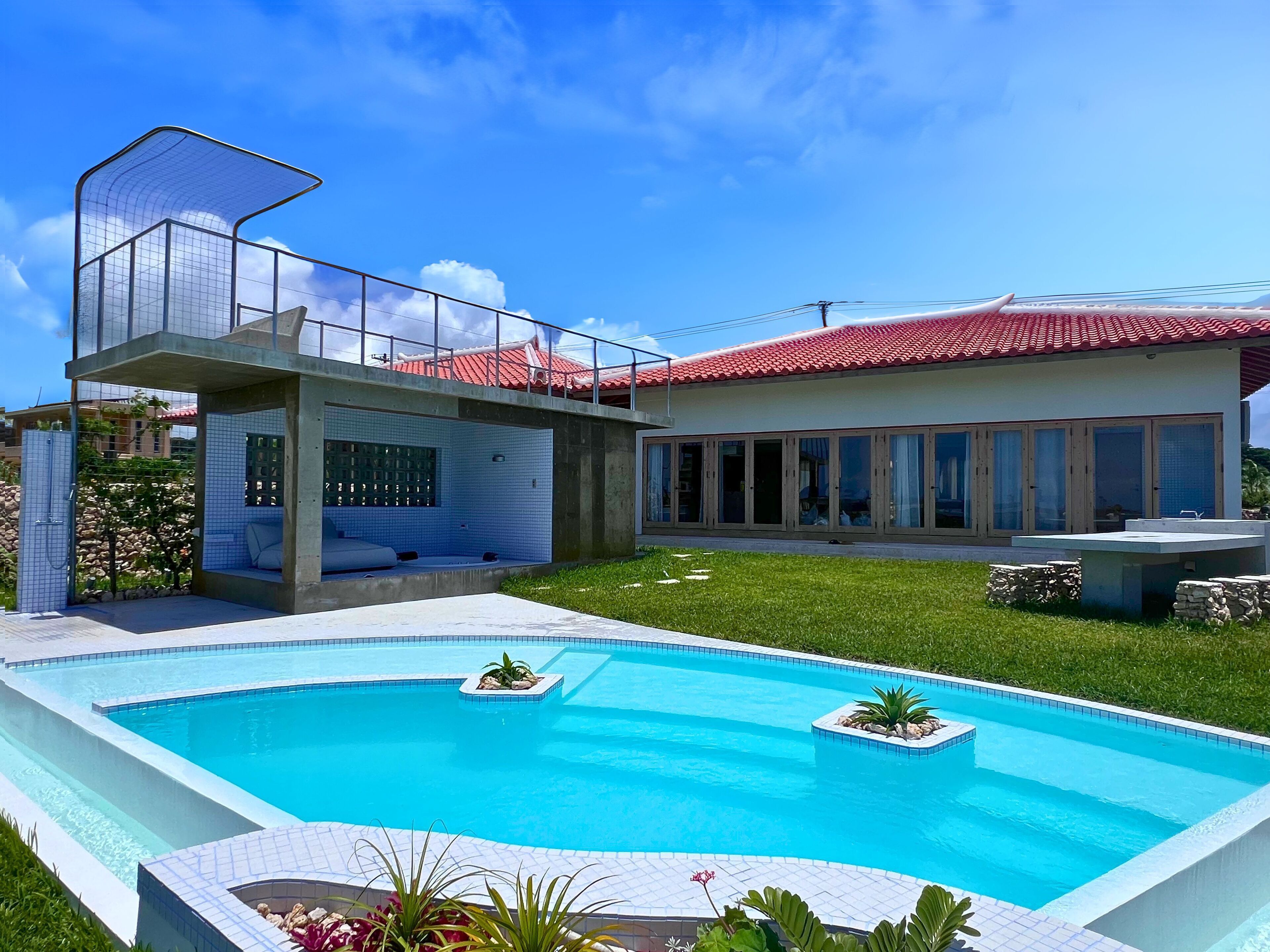Uma casa moderna com piscina, um alpendre coberto e um telhado de telhas vermelhas.