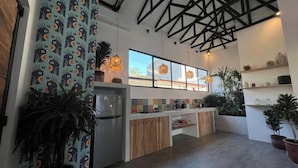 Uma cozinha moderna com geladeira, armários de madeira, painel de azulejos e luminárias pendentes.