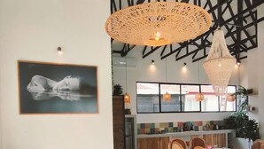 Uma sala de estar moderna com um sofá seccional, uma mesa de centro de madeira com uma planta, e uma área de jantar com mesa e cadeiras de madeira.