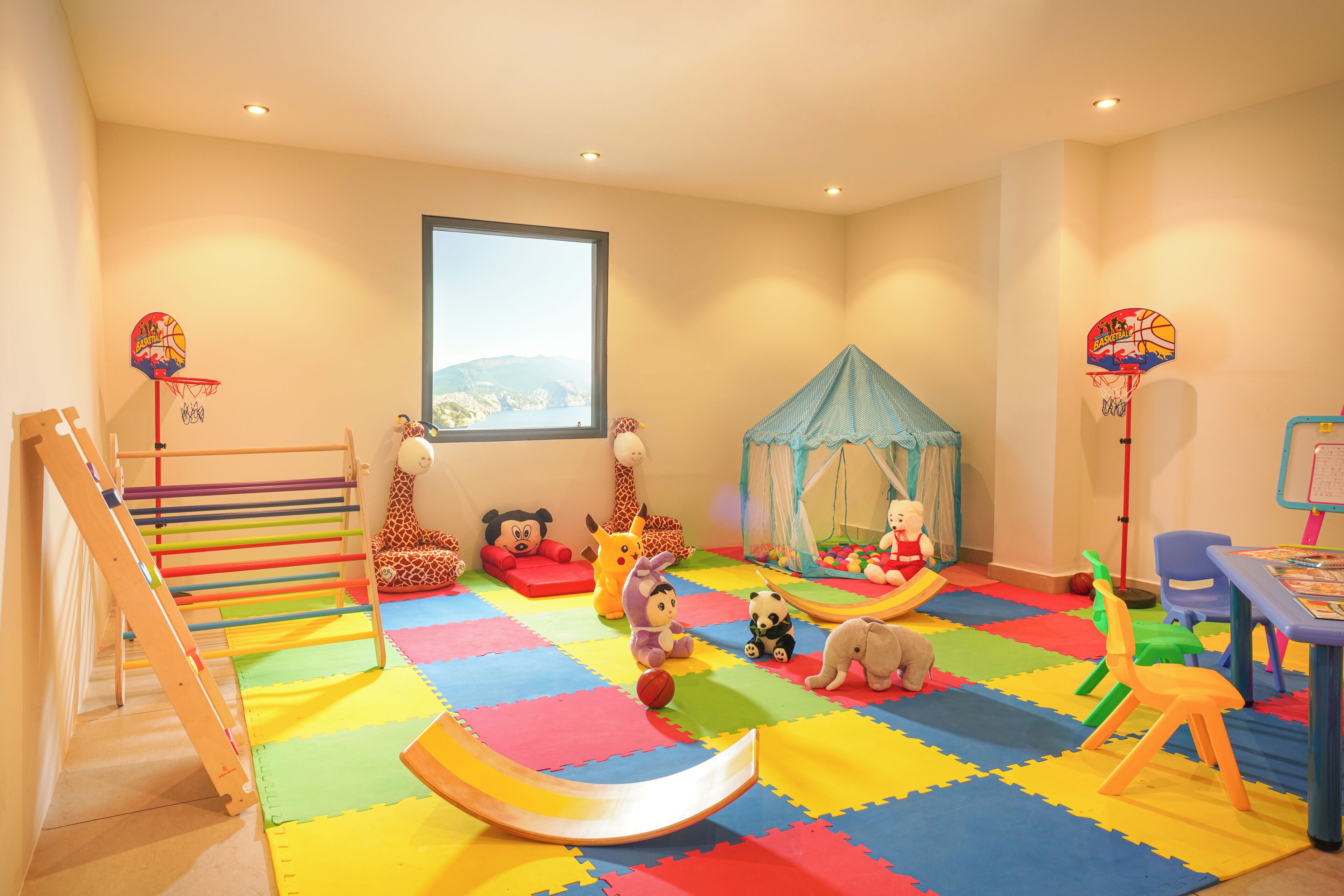 Uma sala de jogos infantil com escorrega, tapetes de atividades e diversos brinquedos.