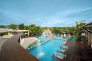 Uma piscina com escorregador, área de recreação aquática e uma estátua de coelho rosa.