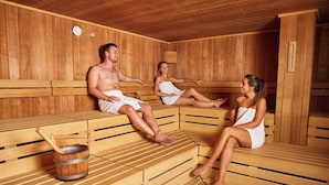Uma sauna com bancos de madeira e um balde de madeira com uma concha.