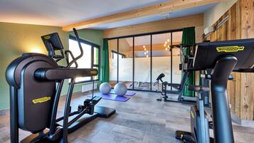 Uma academia com equipamentos de cardio, tapete de yoga e bolas de exercícios.