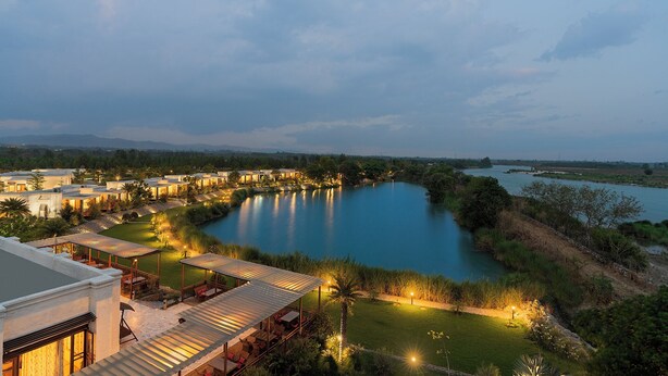 Um resort com vários edifícios, um rio e um gramado bem cuidado.