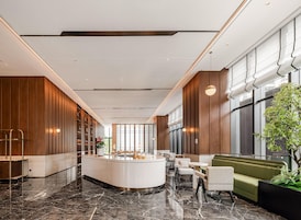 Um lobby moderno com balcão de recepção, área de estar e grandes janelas.