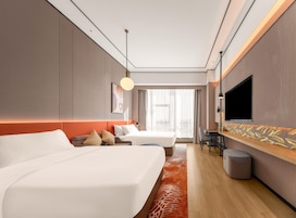 Quarto de hotel moderno com uma cama grande, uma mesa de escritório, televisão e vista para a cidade.