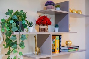 Estante com diversos objetos decorativos, incluindo plantas, uma pequena estatueta e livros.