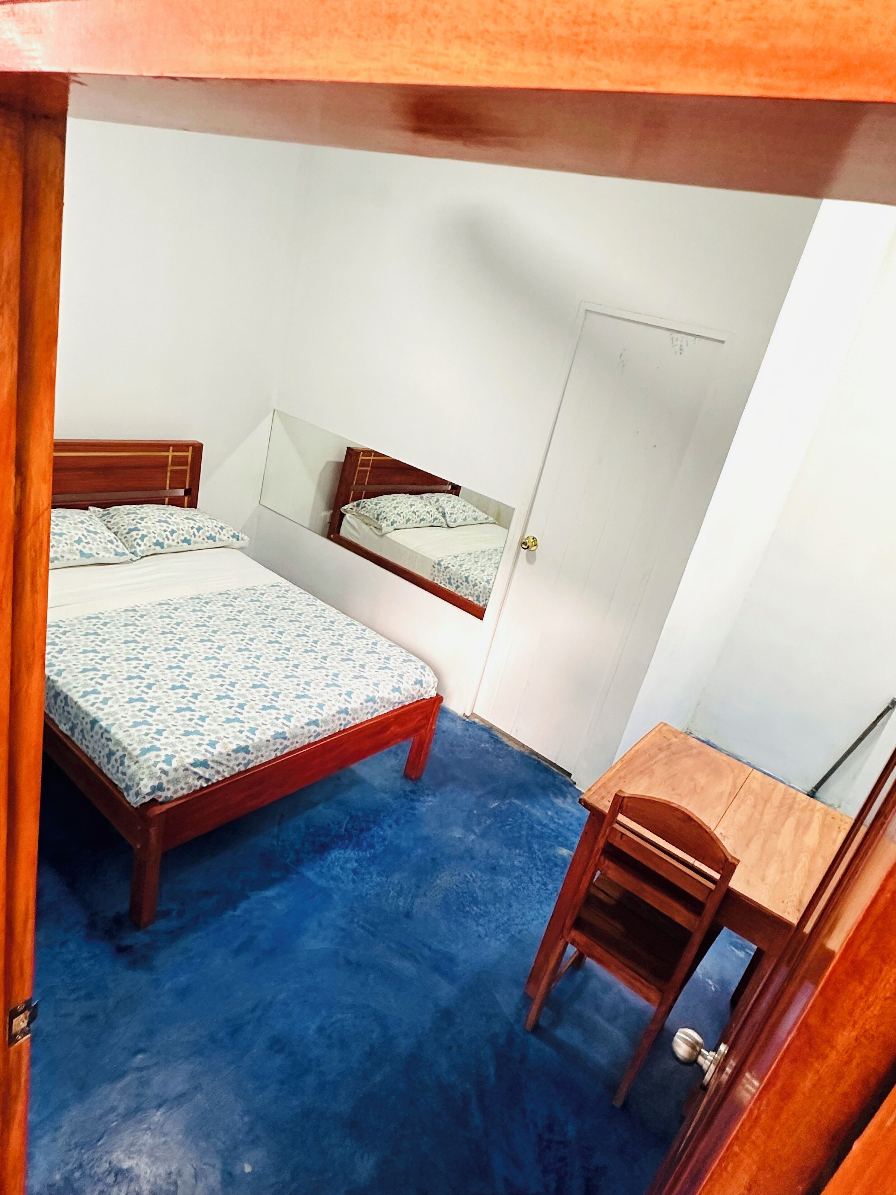 Um quarto com uma cama, uma cadeira e um espelho.