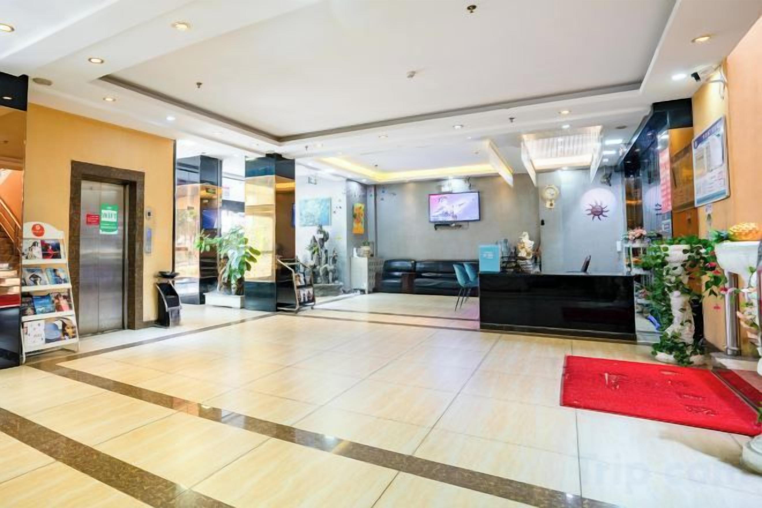 Um saguão de hotel com balcão de recepção, escada e televisão de tela plana na parede.