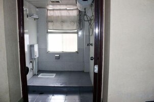Corredor estreito que dá para um banheiro com janela, secador de mãos e porta-toalhas.