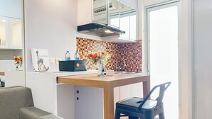 Cozinha moderna com revestimento de azulejos, coifa de aço inoxidável e mesa de jantar de madeira.