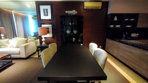 Uma sala de estar moderna com uma mesa de jantar, sofá e cadeiras. Há uma área de cozinha com bancada e armários.