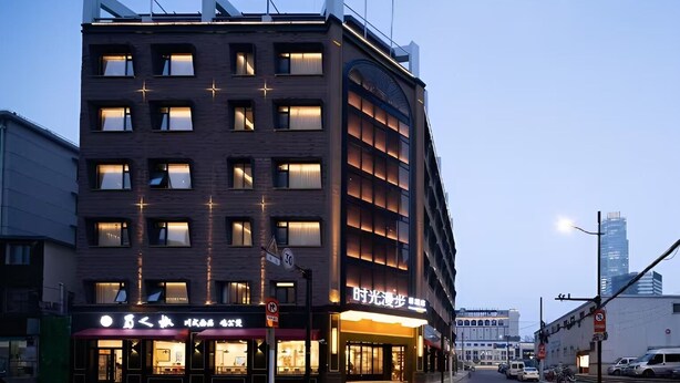 Um hotel com vários andares e design moderno, com uma entrada destacada e sinalização iluminada.