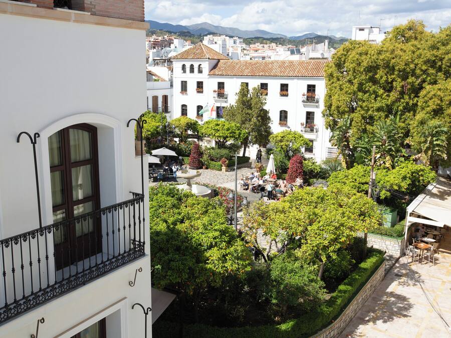 Um pátio com uma fonte, áreas de estar e vista para edifícios ao redor.