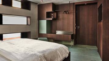 Quarto moderno com cama grande, roupeiro embutido e banheiro pequeno.