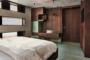 Quarto moderno com cama grande, roupeiro embutido e banheiro pequeno.