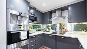 Uma cozinha moderna com eletrodomésticos de aço inoxidável, armários escuros e bancada de madeira.