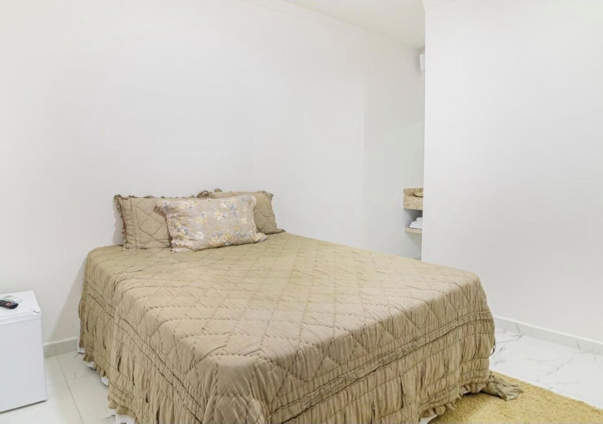Quarto com cama, mesa de cabeceira e uma pequena mesa.