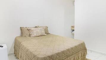 Quarto com cama, mesa de cabeceira e uma pequena mesa.