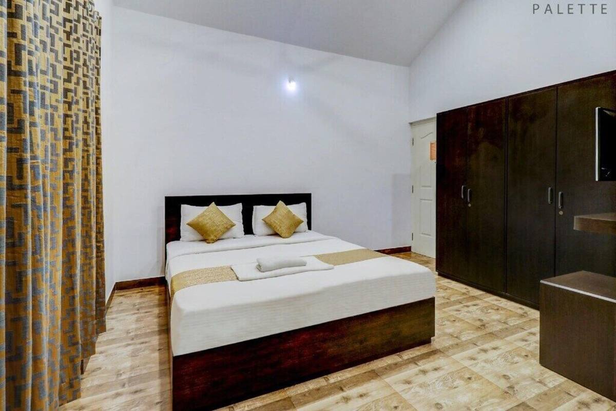 Quarto de hotel com uma cama, um guarda-roupa e uma televisão.
