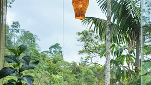 Uma banheira grande em um quarto com vista para vegetação exuberante.