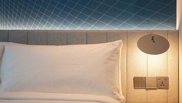 Quarto de hotel moderno com uma cama bem arrumada, luminária fixada na parede e teto texturizado.