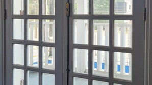 Uma porta branca com vários painéis de vidro, revelando uma área externa com piso de azulejos e parede azul.