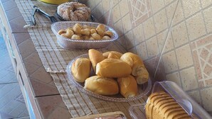 Uma mesa de buffet com diversos alimentos, incluindo pão, doces e queijo.
