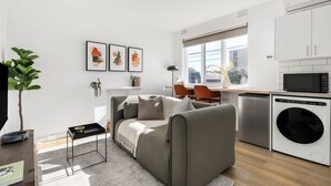 Uma sala de estar moderna com sofá, mesa de centro, máquina de lavar e área de jantar com cadeiras e mesa.